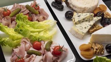 Uma travessa com diversos queijos, carnes e frutas.