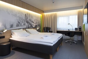 Quarto de hotel moderno com uma cama grande, uma mesa e uma cadeira.