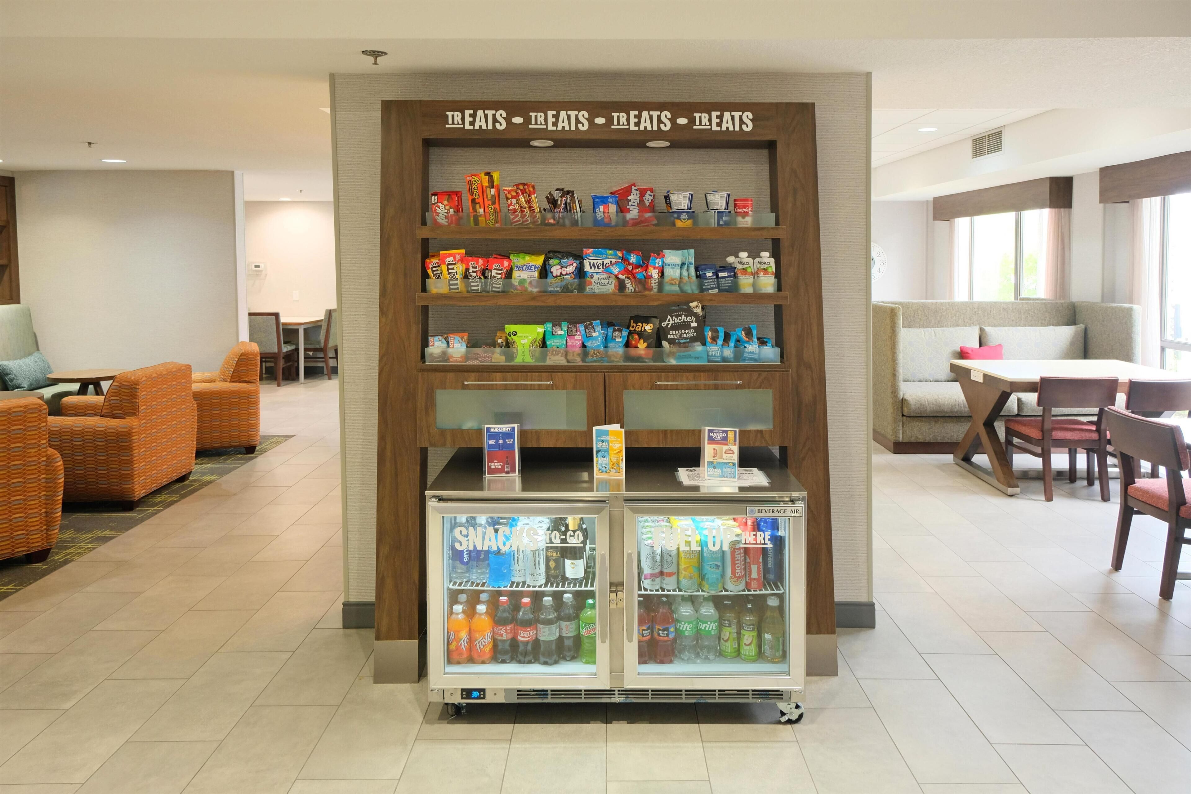 Geladeira para lanches e bebidas no hall de um hotel, com áreas de estar.