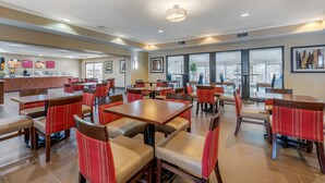 Restaurante com cabines, mesas, balcão e grandes janelas.
