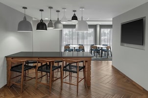Uma sala de jantar moderna com mesa e cadeiras de madeira, iluminação pendente e uma janela grande com cortinas.
