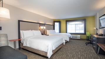 Quarto de hotel com duas camas, uma escrivaninha, uma cadeira, uma televisão e uma janela.