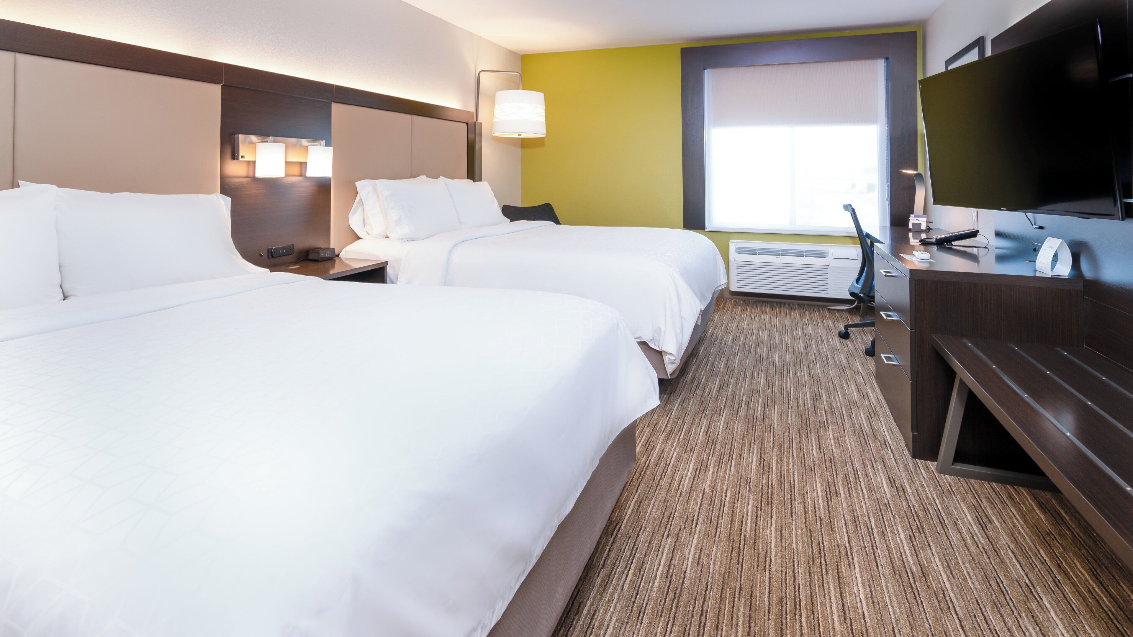 Quarto de hotel com duas camas, televisão, escrivaninha e janela.