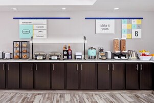 Um balcão de pequeno-almoço com menu, estação de café e exposição de comida.