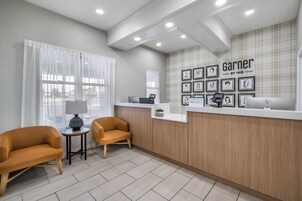 Uma área de recepção com balcão de check-in, obras de arte emolduradas e dois poltronas.