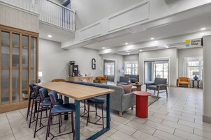 Um espaço amplo e interno com mesa de jantar, cadeiras, sofás e cozinha.