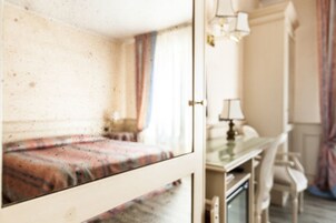 Um quarto com uma cama, uma escrivaninha e um abajur.