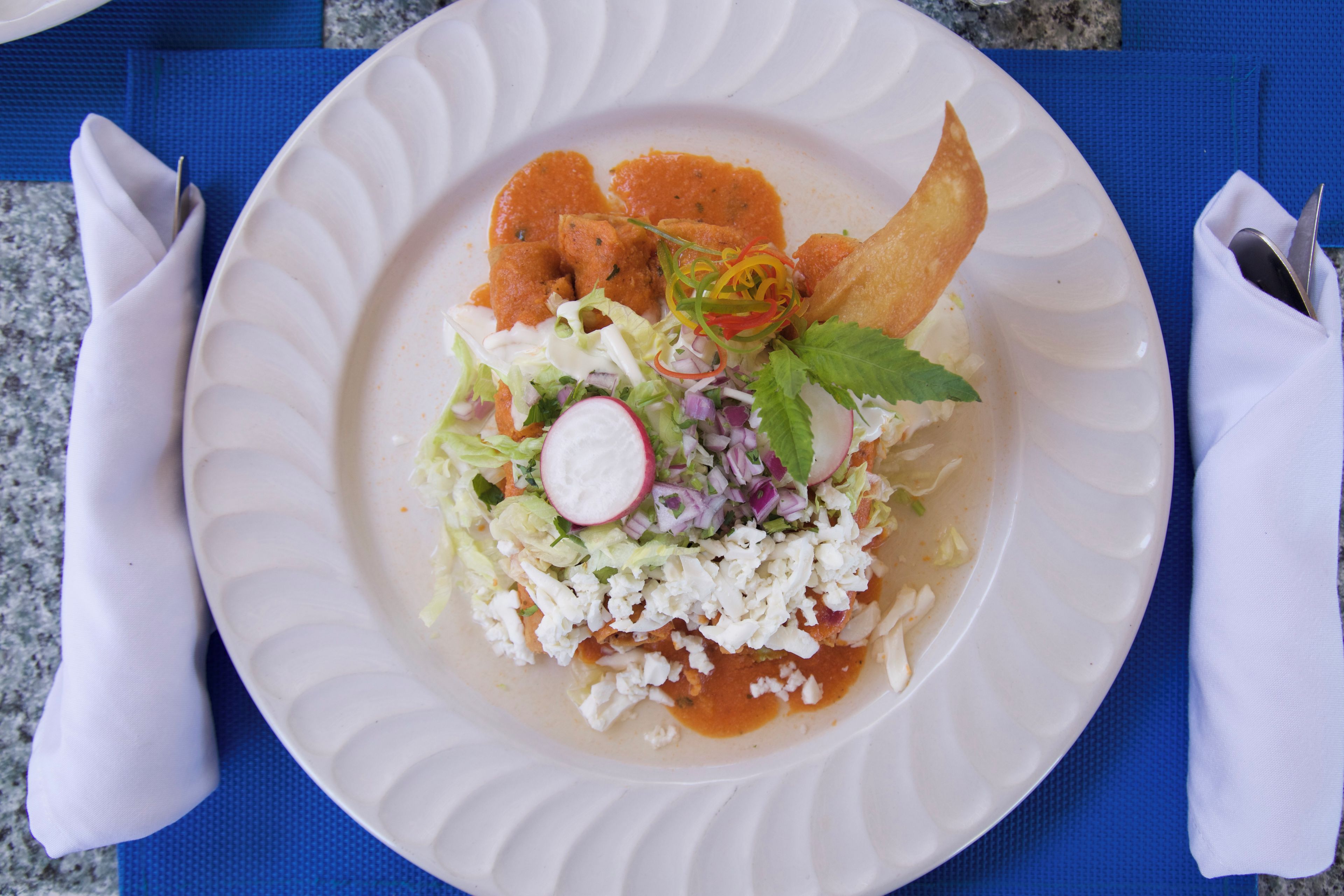 Prato de comida com prato branco, jogo americano azul e guardanapo branco com uma colher.