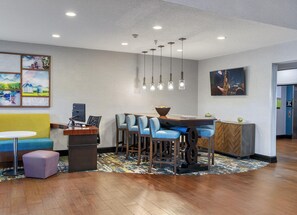 Um hall de hotel moderno com área de bar, assentos e obras de arte nas paredes.