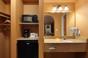 Casa de banho com micro-ondas, máquina de café e pia com porta-toalhas.