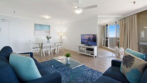 Uma sala de estar moderna com sofá, mesa de centro, televisão e área de jantar.