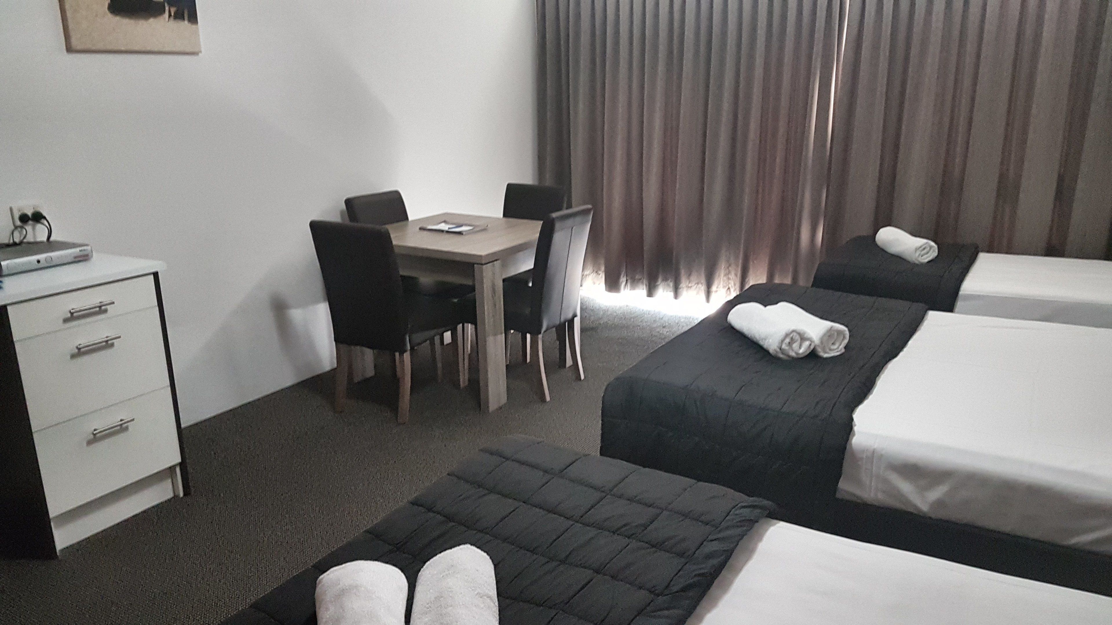 Quarto de hotel com cama, escrivaninha, cadeira e cómoda.