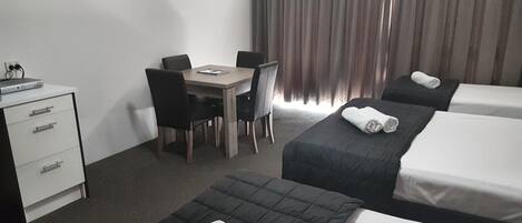 Quarto de hotel com cama, escrivaninha, cadeira e cómoda.