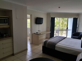 Quarto de hotel com cama, escrivaninha, televisão, cadeira e vista para o exterior.