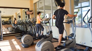 Uma academia com várias esteiras, espelhos e equipamentos de ginástica.