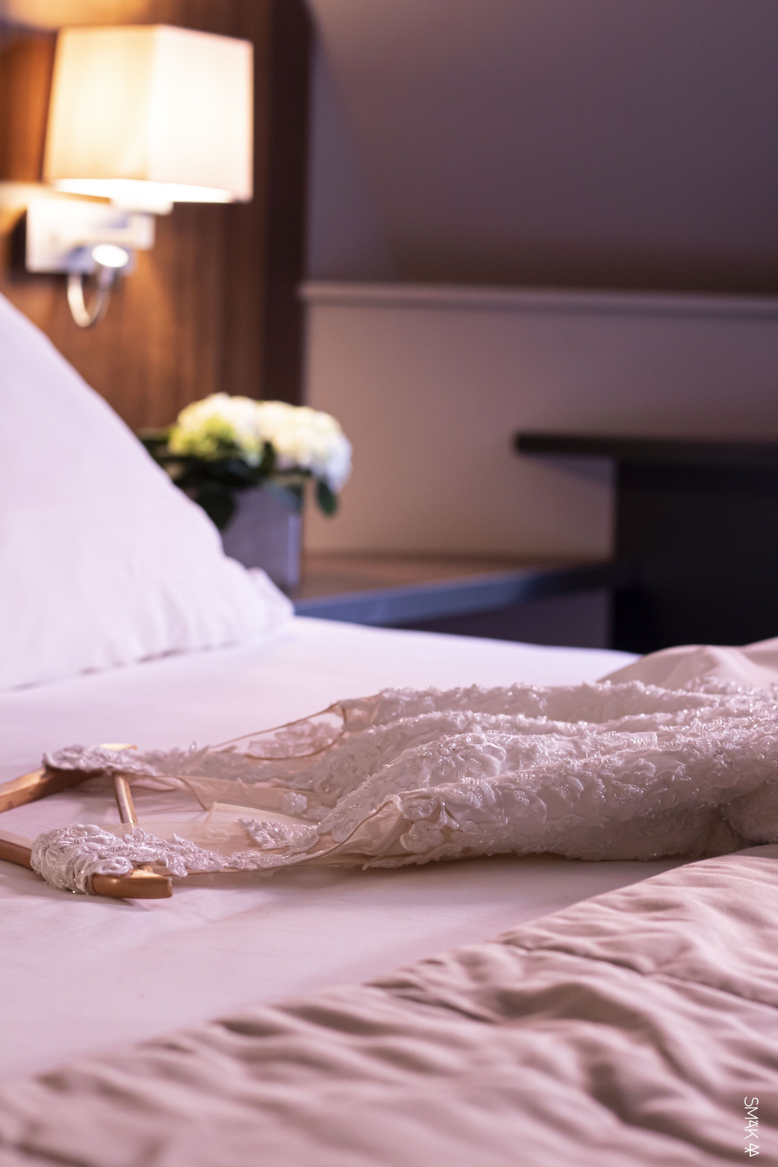 Uma cama com um cobreleto de renda branca e uma cabeceira de madeira.