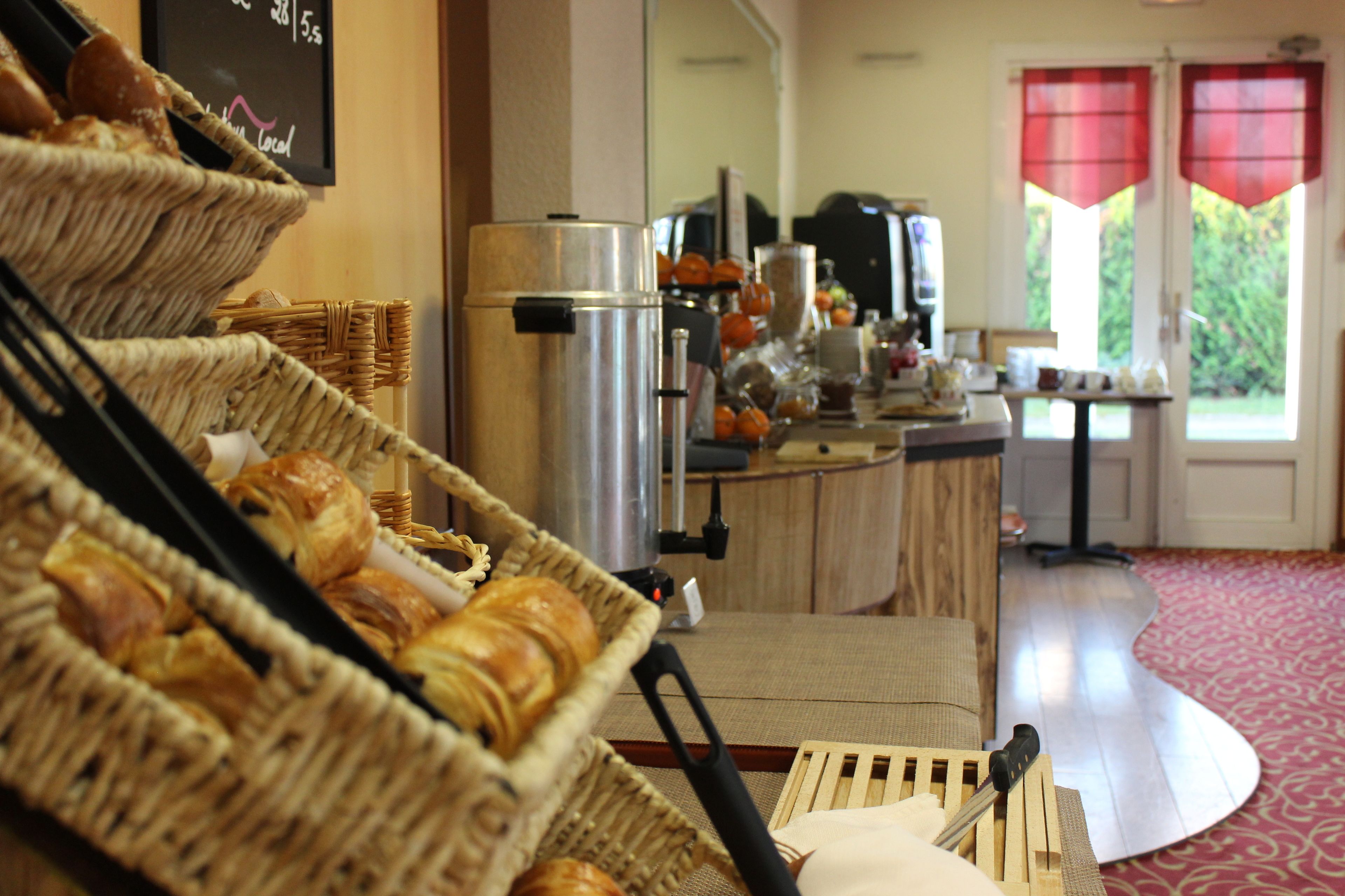 Buffet de café da manhã com cestas de doces e uma máquina de café.