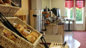 Buffet de café da manhã com cestas de doces e uma máquina de café.