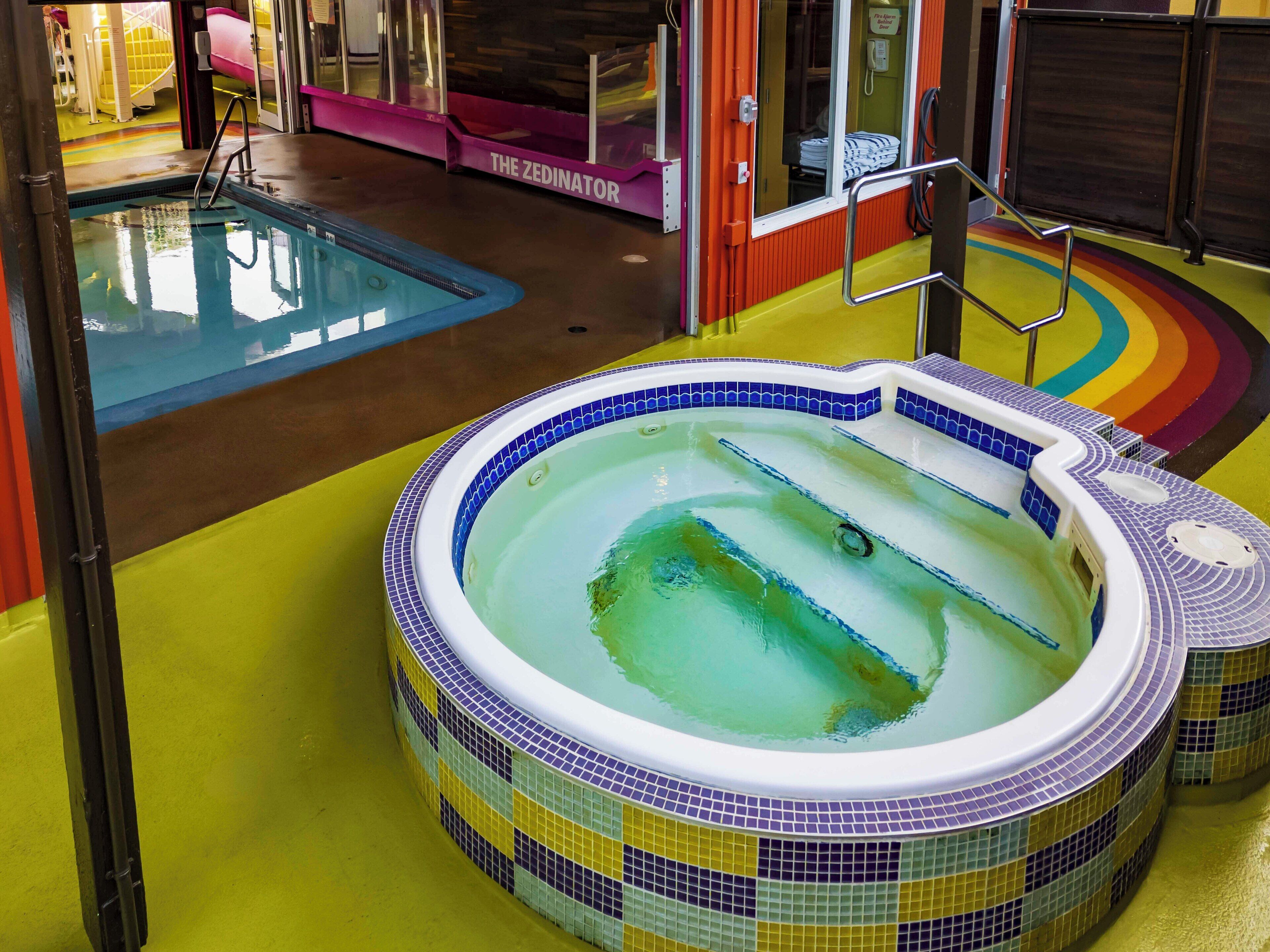 Uma área de piscina interna colorida, com uma banheira de hidromassagem e uma piscina menor.