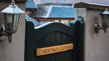 Uma entrada fechada por portão com uma placa que diz 'Chestnut Cottage'.