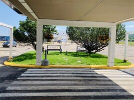 Uma área externa coberta com uma passadeira a conduzir a um parque de estacionamento.