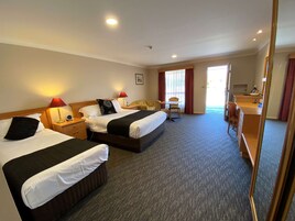 Quarto de hotel com duas camas, uma escrivaninha, uma cadeira e vista para o oceano.