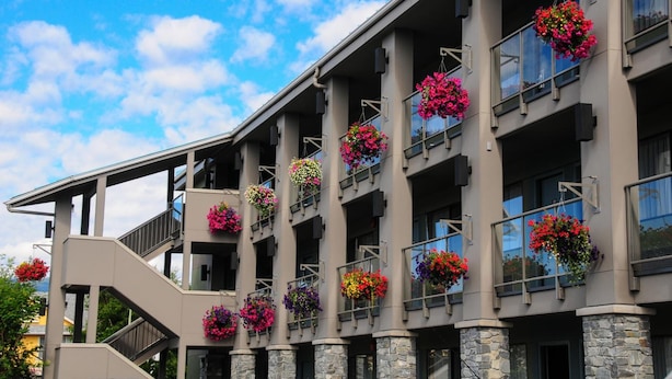 Um edifício com vários andares e varandas decoradas com cestos de flores coloridas.