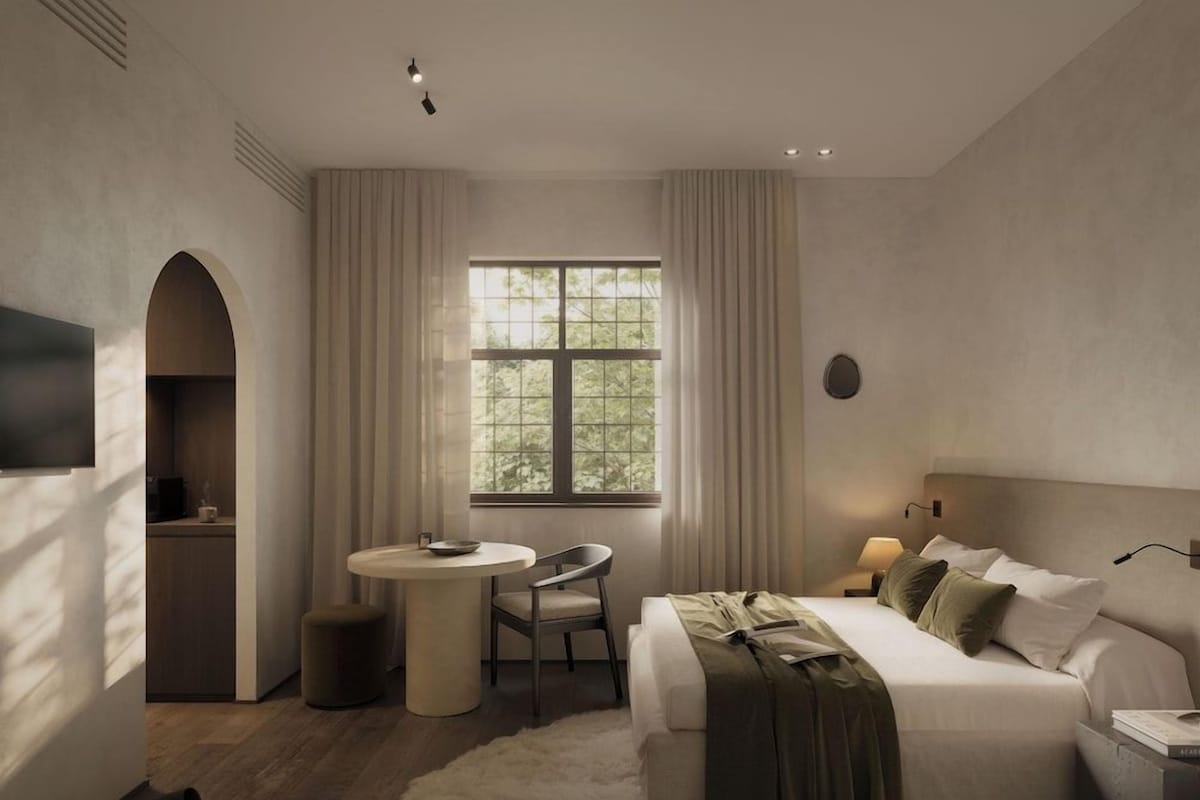 Quarto de hotel moderno com cama, mesa redonda, cadeira e janela.