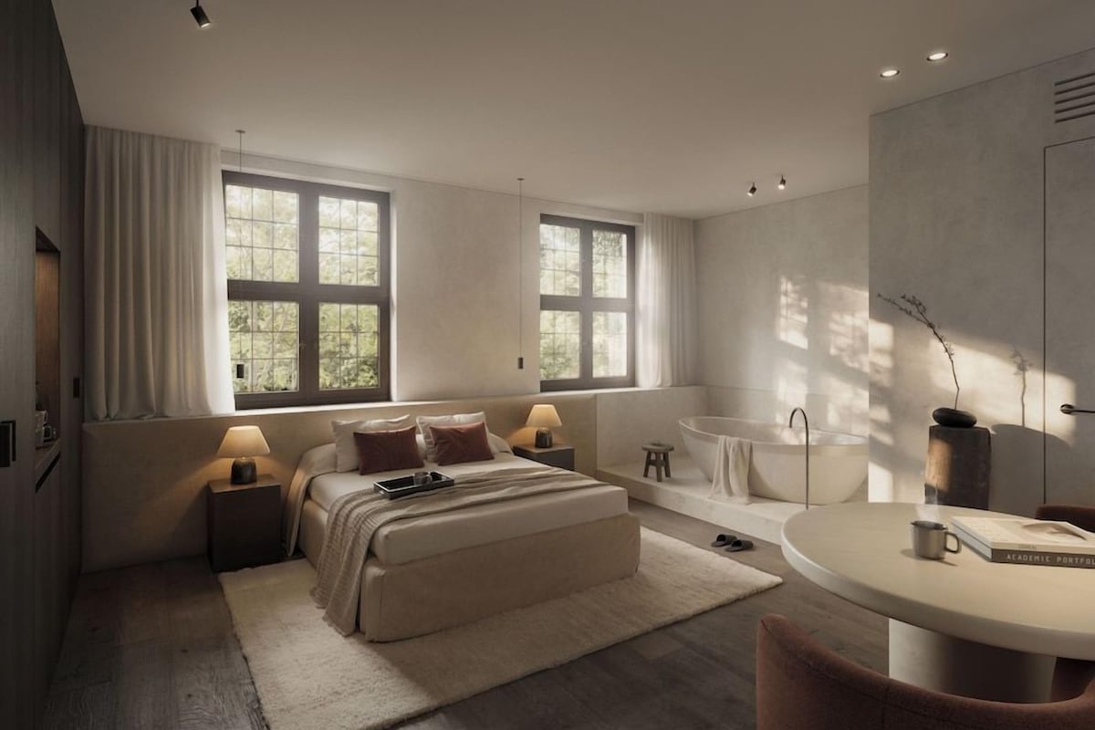 Quarto moderno com cama grande, mesas de cabeceira, penteadeira e banheira.