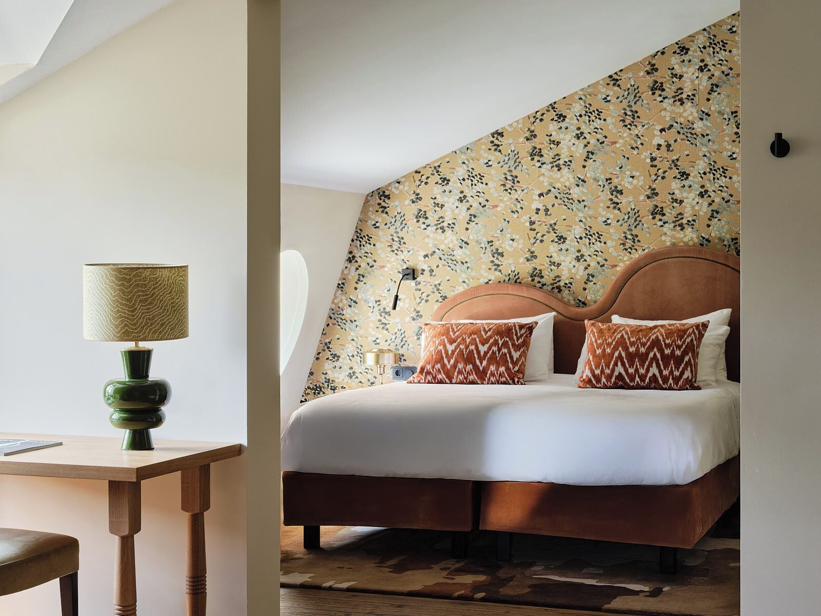 Quarto de hotel com cama, escrivaninha e luminária.