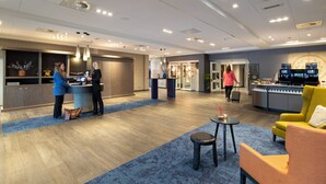 Um lobby moderno de hotel com balcão de recepção, área de estar e bar.