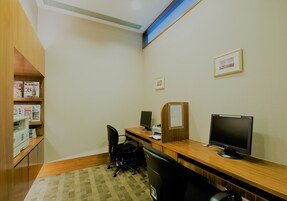 Um escritório pequeno com uma mesa, computador, cadeira e um mural.