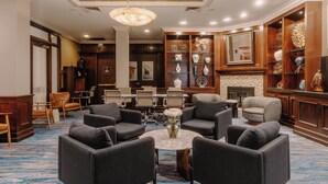 Um hall amplo com área de estar central, lareira e diversos objetos decorativos nas prateleiras.