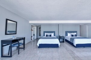 Quarto de hotel com duas camas, uma escrivaninha e uma cadeira.