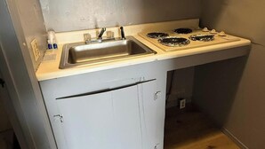 Cozinha compacta com pia, fogão e um pequeno armário.