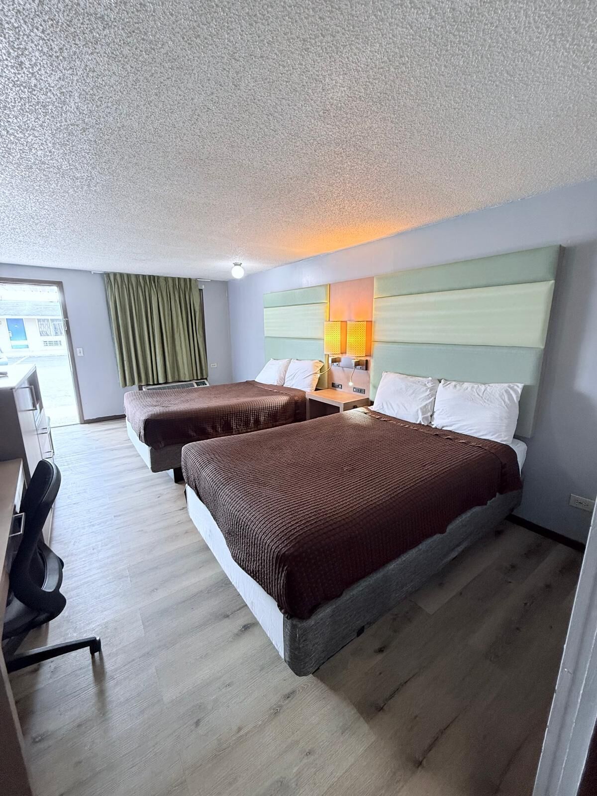 Quarto de hotel com duas camas, uma mesa e uma cadeira.