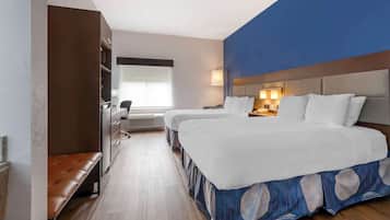 Quarto de hotel com duas camas, um banco, uma escrivaninha e um guarda-roupa.