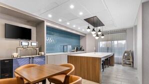 Cozinha moderna com ilha de madeira, TV embutida e espaço para bar.