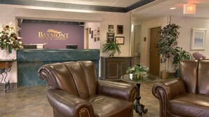 Um saguão com poltronas de couro, um balcão de recepção e uma área de recepção com uma placa que diz "Baymont Inn & Suites".