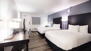 Quarto de hotel com duas camas, uma mesa de escritório com computador e telefone, e uma janela.