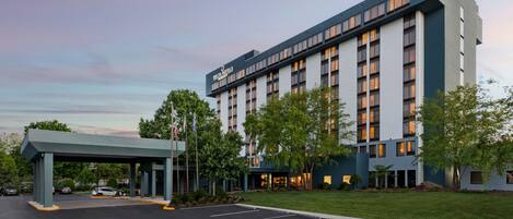 Edifício da Delta Hotels com design moderno, área de estacionamento coberta e gramado bem cuidado.