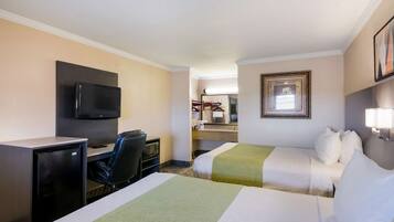 Quarto de hotel com duas camas, uma escrivaninha com computador, televisão e um pequeno frigorífico.