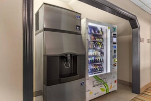 Máquina automática com dispensador de água e diversas opções de lanches e bebidas.