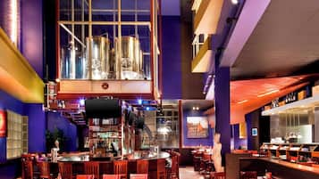 Restaurante com área de bar, diversos arranjos de assentos e uma grande janela com vista para o interior.