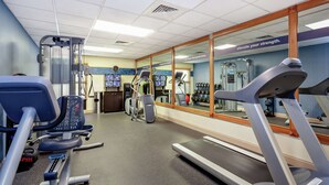 Uma academia com esteiras, aparelhos de musculação e um espelho com frases motivacionais.
