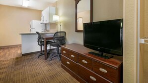 Quarto de hotel com cômoda de madeira, televisão de tela plana, escrivaninha com cadeira, micro-ondas e espelho grande.