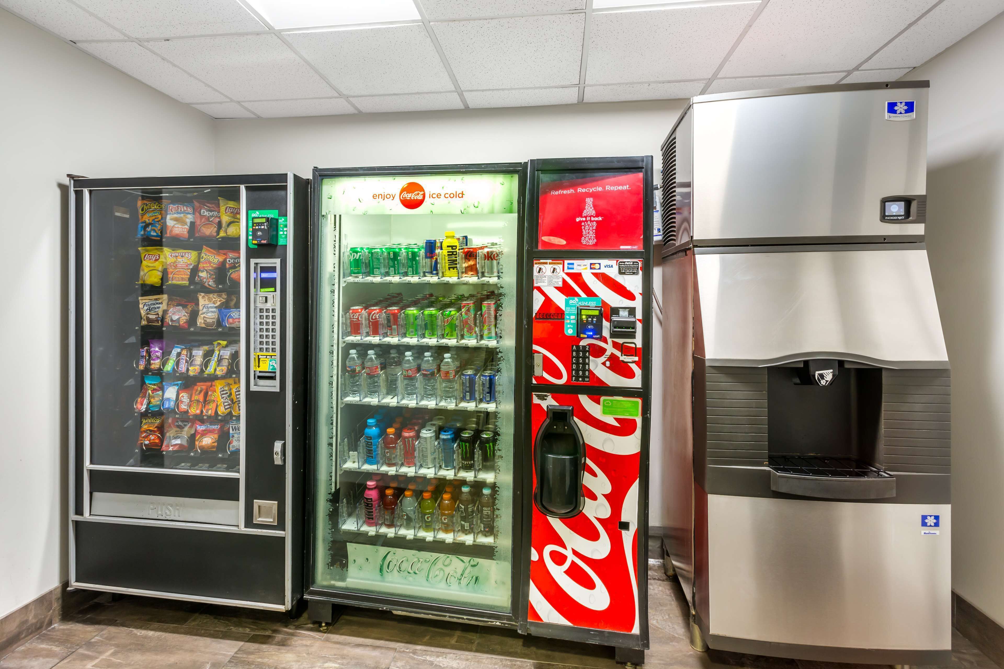 Uma área com máquinas de venda automática, oferecendo lanches, Coca-Cola e água.