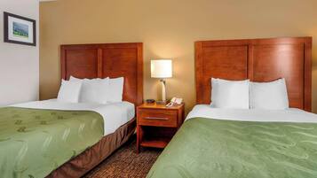 Quarto de hotel com duas camas de solteiro, mesa de cabeceira com abajur e quadro na parede.