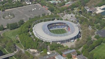 Vista aérea de um estádio cercado por vegetação e edifícios.
