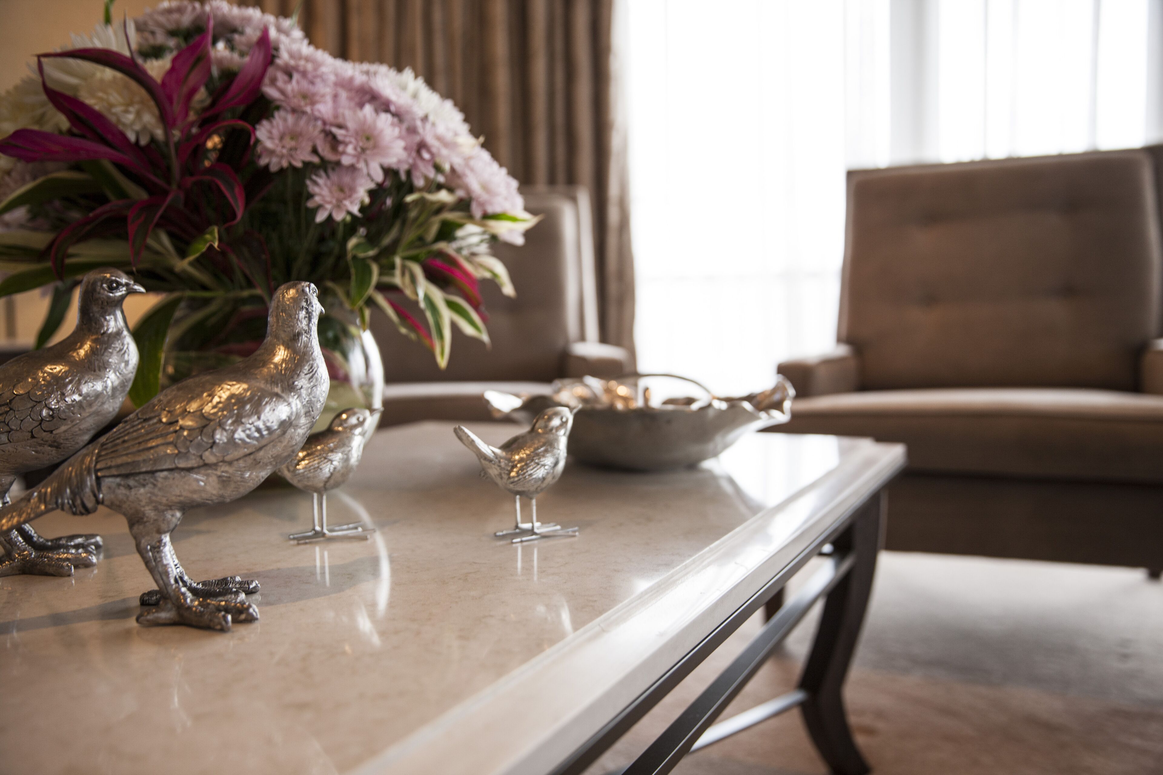 Uma sala de estar com uma mesa de centro de mármore, um vaso de flores e um sofá.
